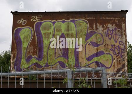 An old rusty water tank covered with graffiti sits in the setting sun ...