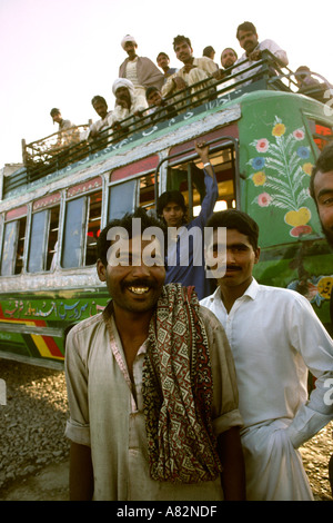 Overloaded public transport bus carrying people on top and hanging out ...
