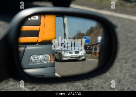 Drivers view of lorries in wing mirror of a car on a busy motorway in ...