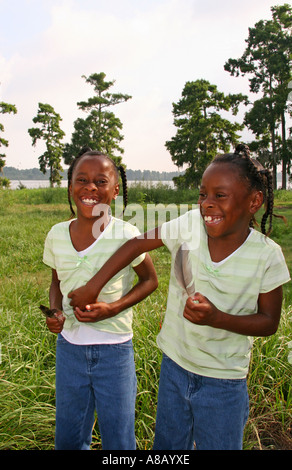 Two black sisters playing with each other, the small one sitting on the ...