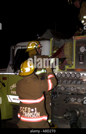 Fireman loading hose back on fire truck at a night fire drill Stock ...