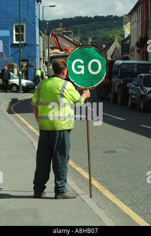 Workman operating stop go board to control traffic movement through ...