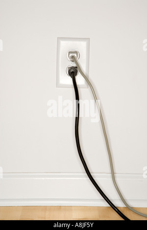 Two cords plugged into electrical wall outlet Stock Photo - Alamy