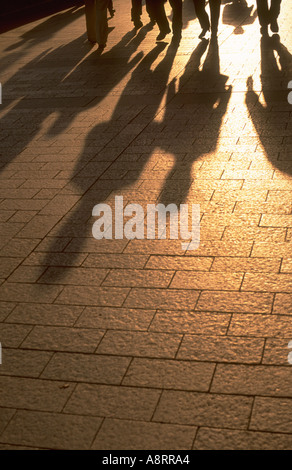 Long shadows of people walking in town at sunset Stock Photo - Alamy