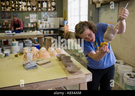Woman dipping unfired ceramic pottery in a Shino glaze, River Arts ...