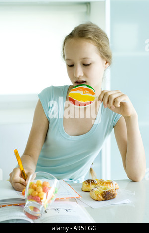 Girl eating sweets and doing homework Stock Photo - Alamy