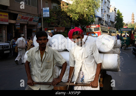 Indian male porters pulling heavy wagon load through streets of ...