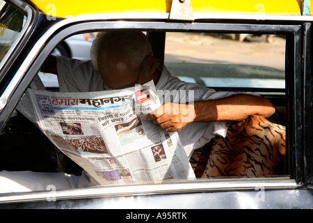 Indian Taxi driver reading Indian newspaper in his padmini taxi, Mumbai ...