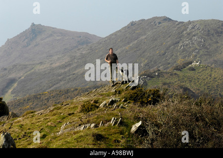 Shepherd David Kennard walks out over rocky ground with sheepdog to ...