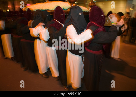 Hooded members of a fraternity carry a float during Holy Week ...