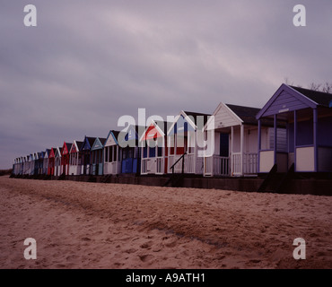 Colorful beach huts lined along a seaside boardwalk with a bright blue ...
