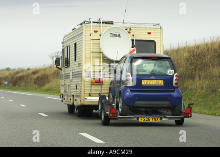Motor home towing a Smart car on a trailer, parked in a M5 motorway ...