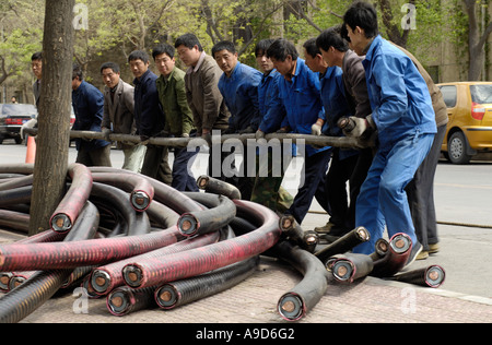 Chinese workers replace electric cables on a street in Beijing China 19 ...