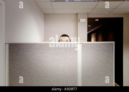 Man peeking over cubicle wall Stock Photo - Alamy