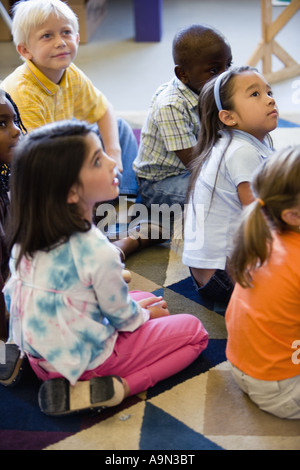 Young children watching and listening attentively in a colorful room ...