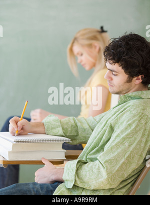 Young pupil writing in his textbook while listening to an online class ...