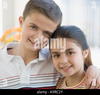 Close-up of happy brother embracing cute sister while standing against ...
