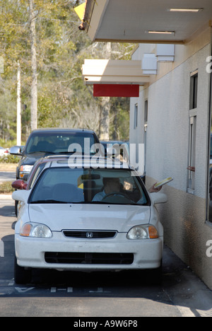 Cars use a drive through window to order and pick up fast food at a ...