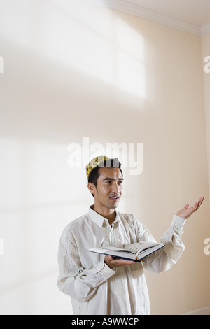 Praying Muslim man with Koran on dark background Stock Photo - Alamy