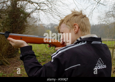teenage boy aiming air rifle at target on a tree trunk Stock Photo - Alamy
