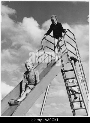 1950s, historical, children playing on a see-saw and swings outside at ...