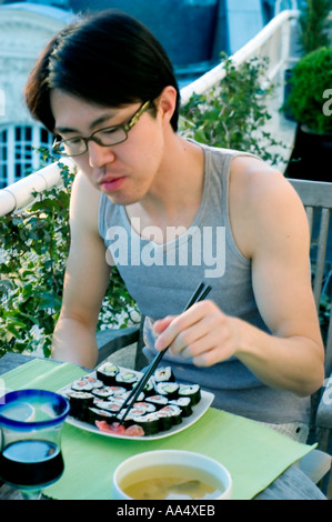 Young man eating asian sushi from home delivery cover mouth with hand ...