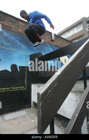 A parkour freerunning athlete vaulting over a wall on a rooftop with ...