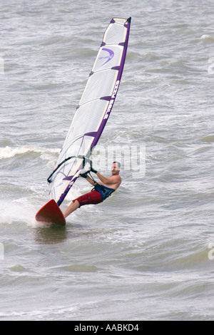 single male windsurfer sailing in gold evening light on azure water of ...