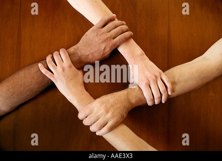 Four arms locked together at the wrists with a pencil cup Stock Photo ...