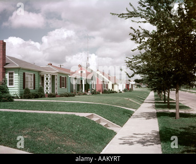 A street of family houses in suburban area with concrete side walk and ...