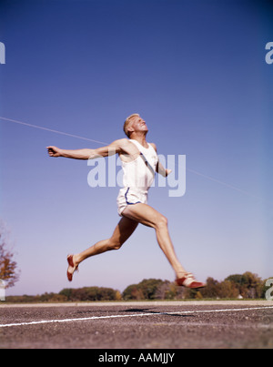 Runner breaking through finish line Stock Photo - Alamy