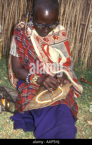 Maasai lady in traditional dress making tea outside at a women's co ...