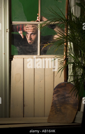 Sinister character peering through a broken window Stock Photo - Alamy