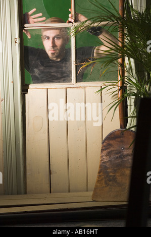 Sinister character peering through a broken window Stock Photo - Alamy