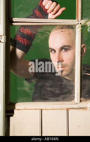 Sinister character peering through a broken window Stock Photo - Alamy