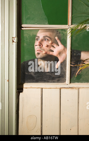 Sinister character peering through a broken window Stock Photo - Alamy