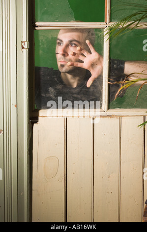 Sinister character peering through a broken window Stock Photo - Alamy