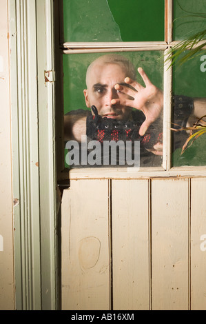 Sinister character peering through a broken window Stock Photo - Alamy