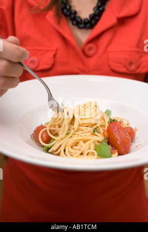 Woman eating spaghetti with tomatoes and basil FoodCollection Stock ...