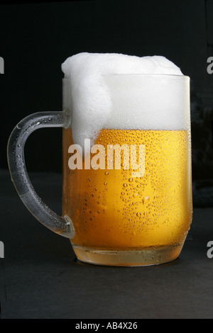 Glass mug with fresh cold beer on wooden bench in winter outdoor cafe ...