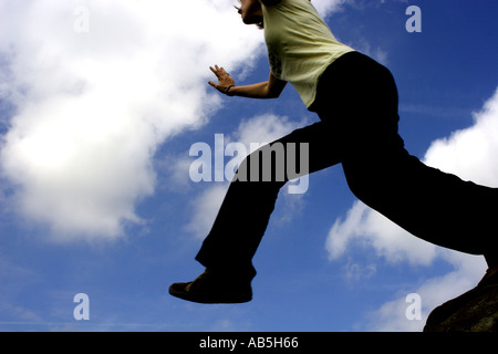 jumping between two rocks with sky and clouds Stock Photo - Alamy