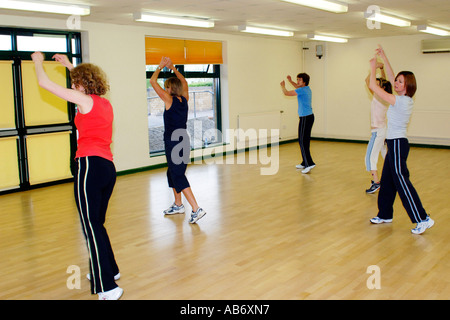 Females doing hip wiggle and clapping exercises in a workout class ...