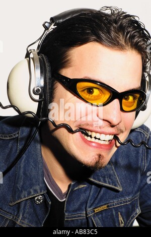Detail shot of a young man biting a marijuana bud with grey background ...