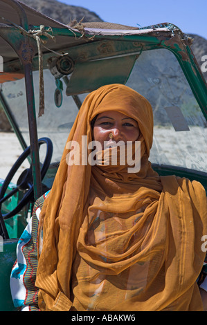 Three quarter portrait Ababda tribeswoman standing by 4x4 land rover in ...