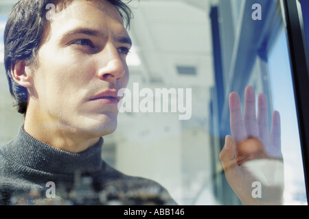 Young businessman looking through window Stock Photo - Alamy
