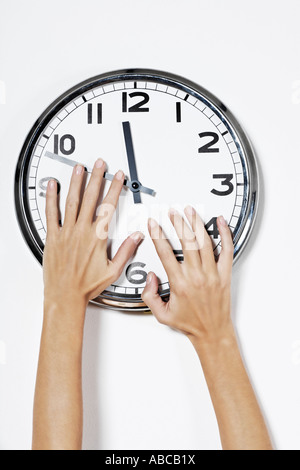 hands trying to stop the advance of the time by grabbing needle of a ...