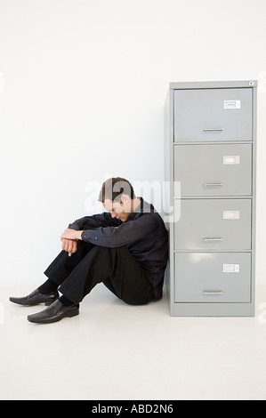 Businessman hiding behind filing cabinet Stock Photo - Alamy