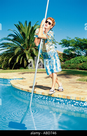Young man is cleaning the swimming pool from underwater with a brush ...