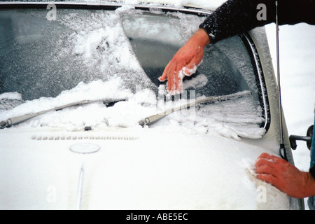 Man scraping off snow and ice from a car automobile after a snow storm ...