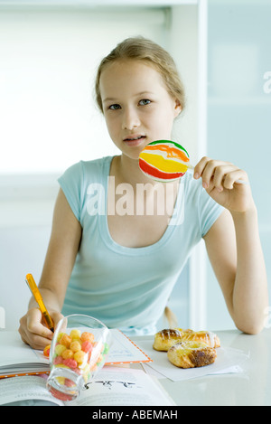 Girl eating sweets and doing homework Stock Photo - Alamy